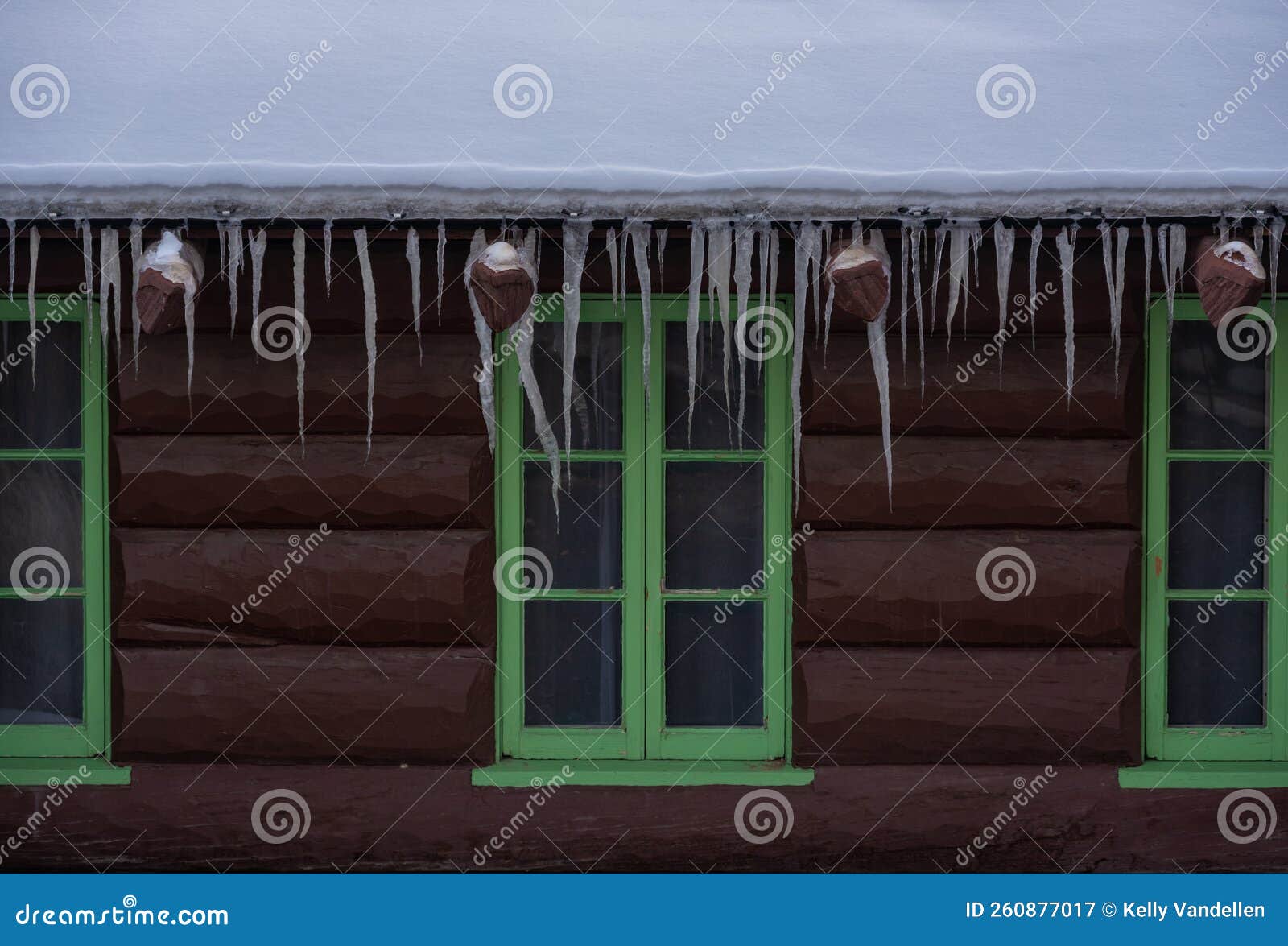 Long Gnarly Icicles Hand Down from Log Cabin Over Green Windows Stock ...