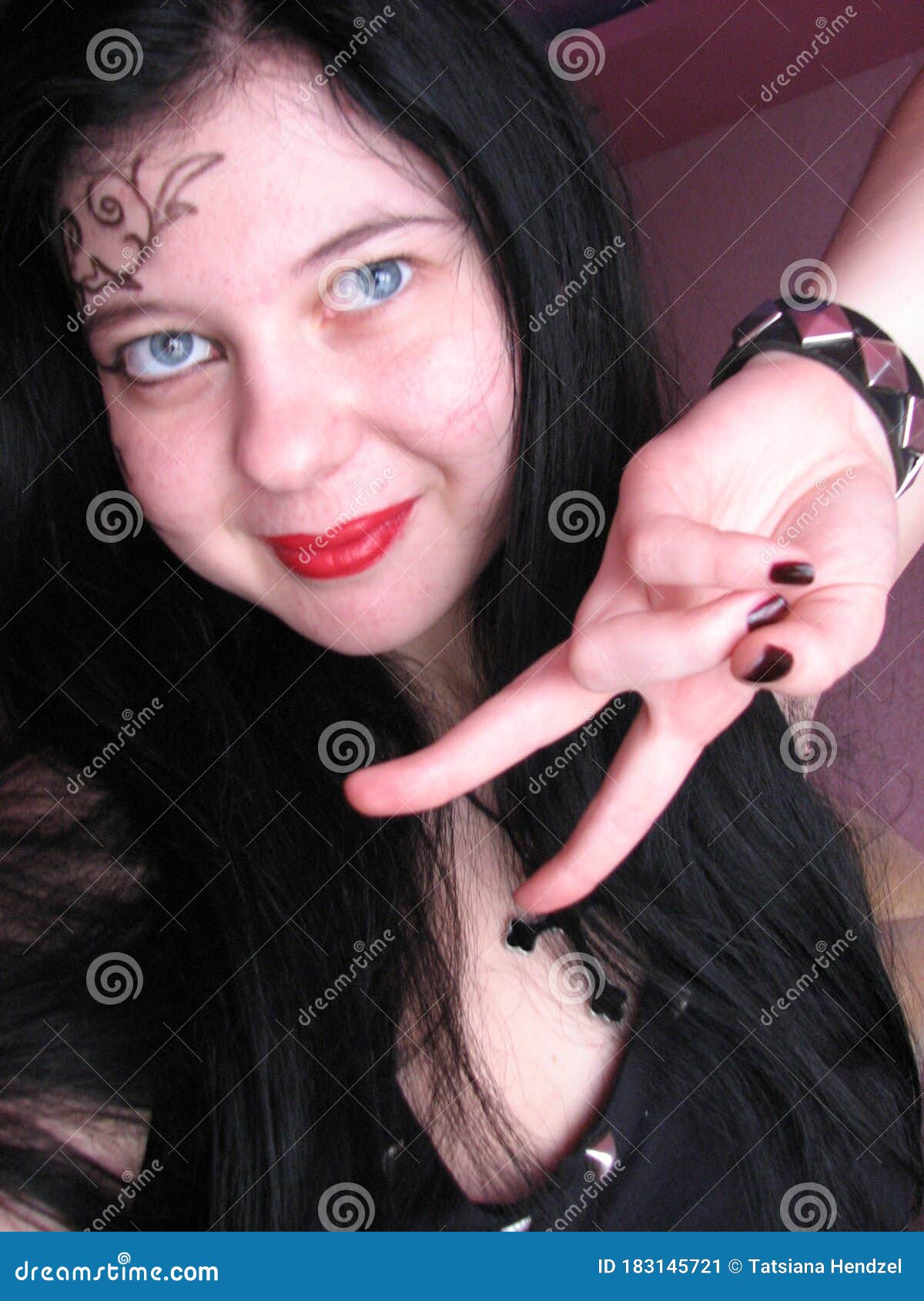 Long Haired Young Caucasian Gothic Girl With Black Hair In Black Clothes With A Cross On Her