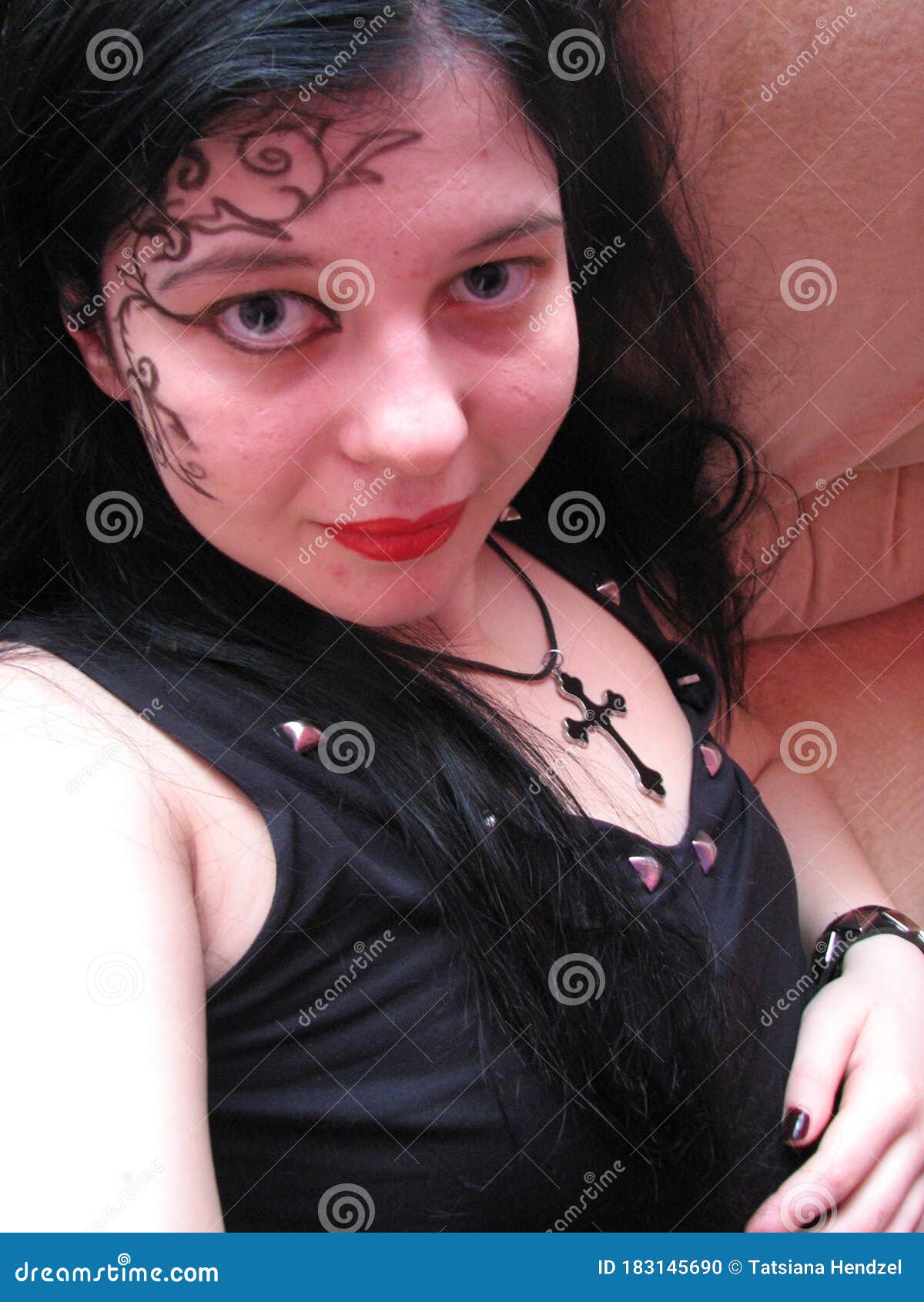 Long Haired Young Caucasian Gothic Girl With Black Hair In Black Clothes With A Cross On Her