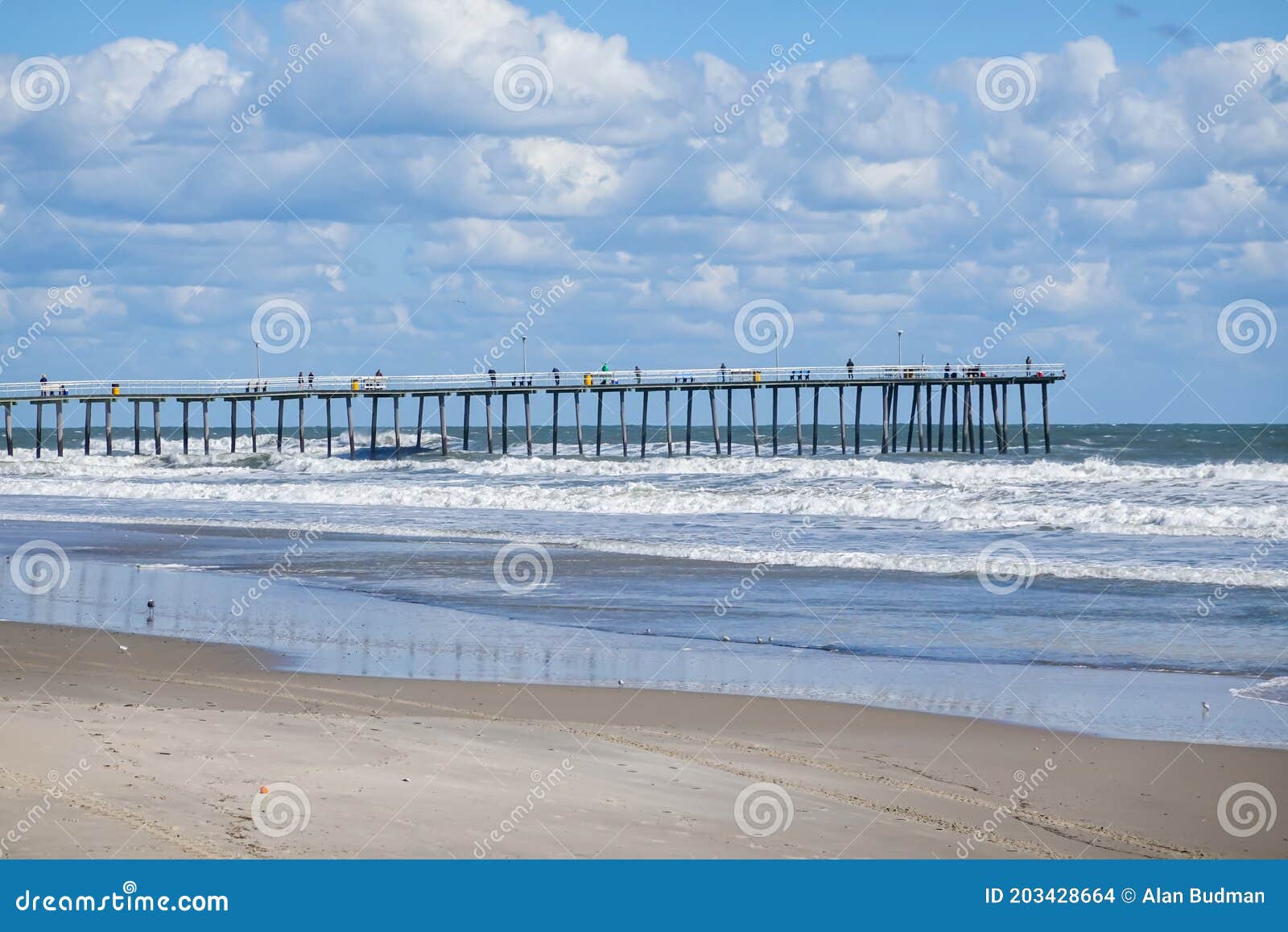 Long Pier Extending from the Beach Out into a Rough Ocean. the Sky is ...