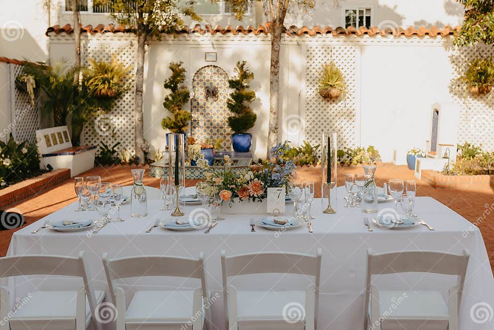 A Long, Rectangular Table Covered in a White Tablecloth is Set for a ...