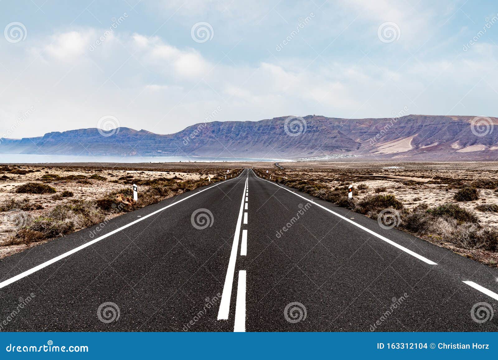 Long Straight Empty Asphalt Road through Arid Landscape Against Ocean ... Long Straight Empty Asphalt Road through Arid Landscape Against Ocean ...