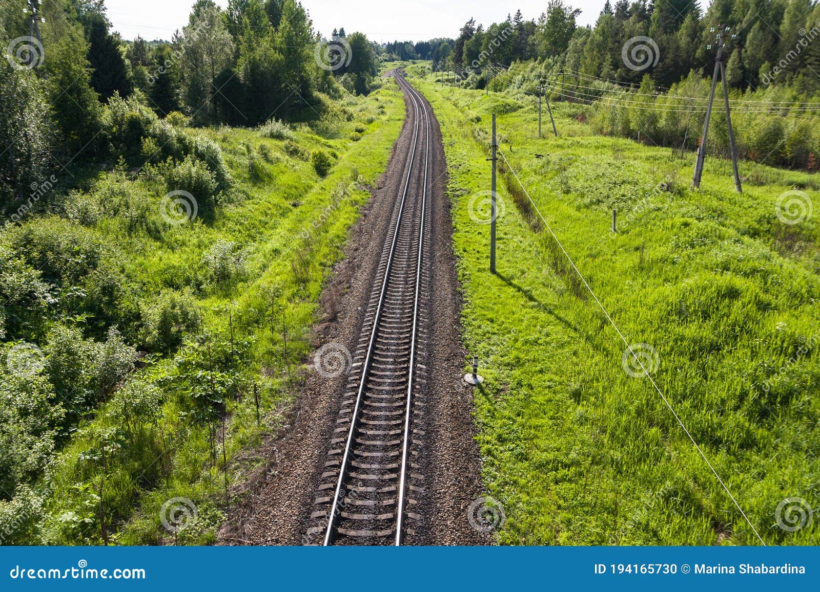 Long Winding Train Track Surrounded by Green Fields and Trees and a ...