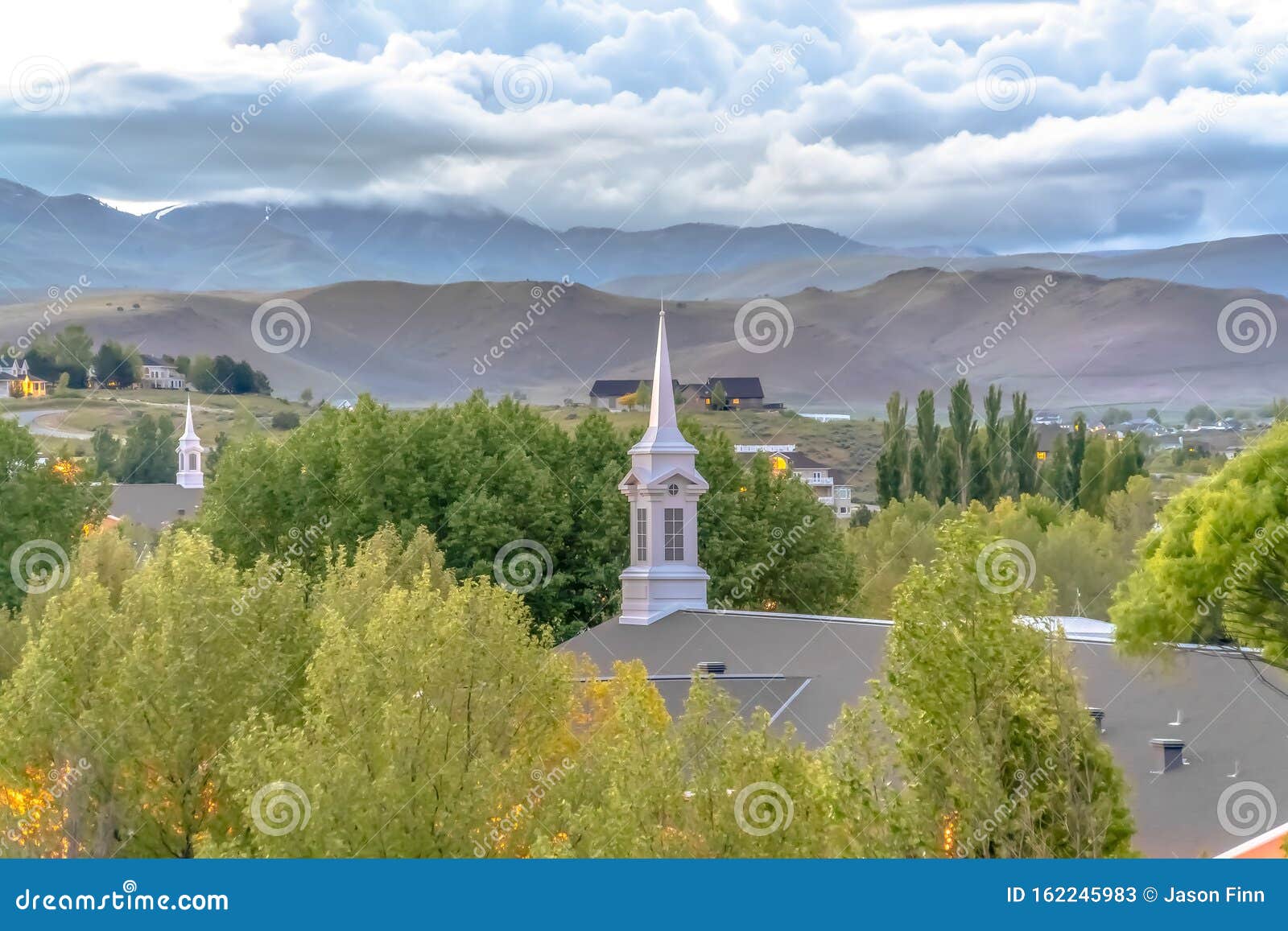 Looking Down at a White Churge Steeple in the Trees with Mountains ...