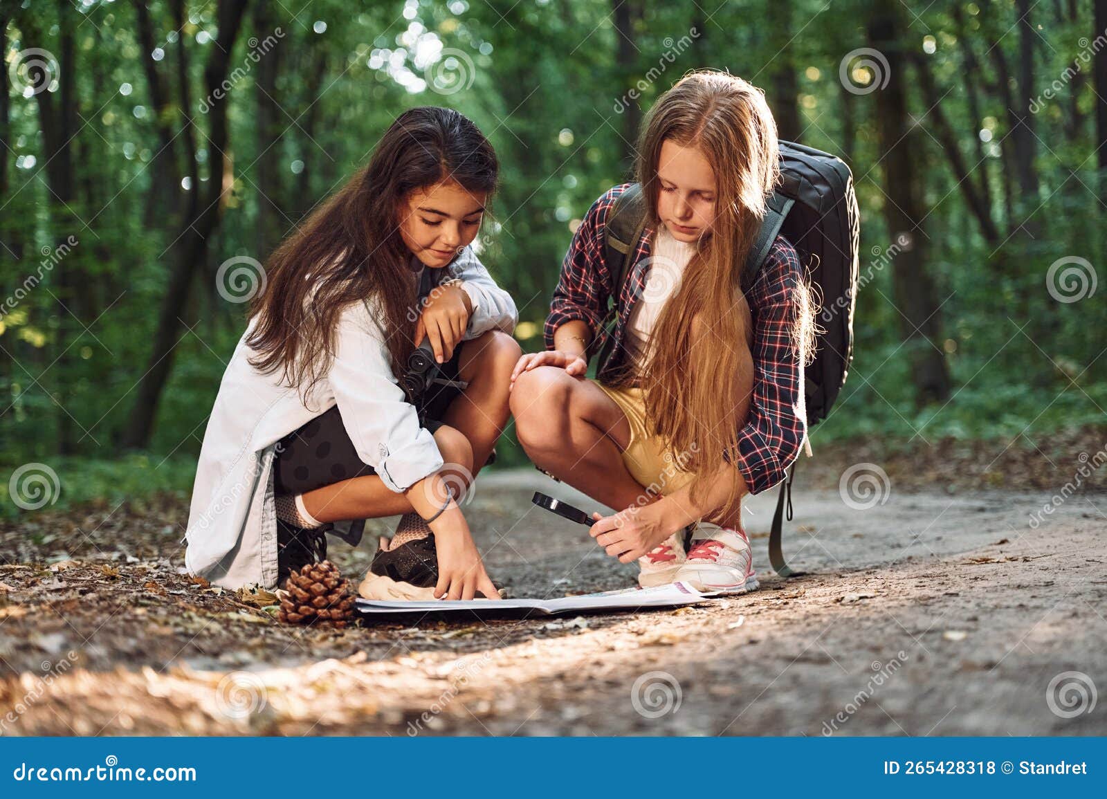 Looking at the Map Hat is on the Ground. Two Girls is in the Forest ...