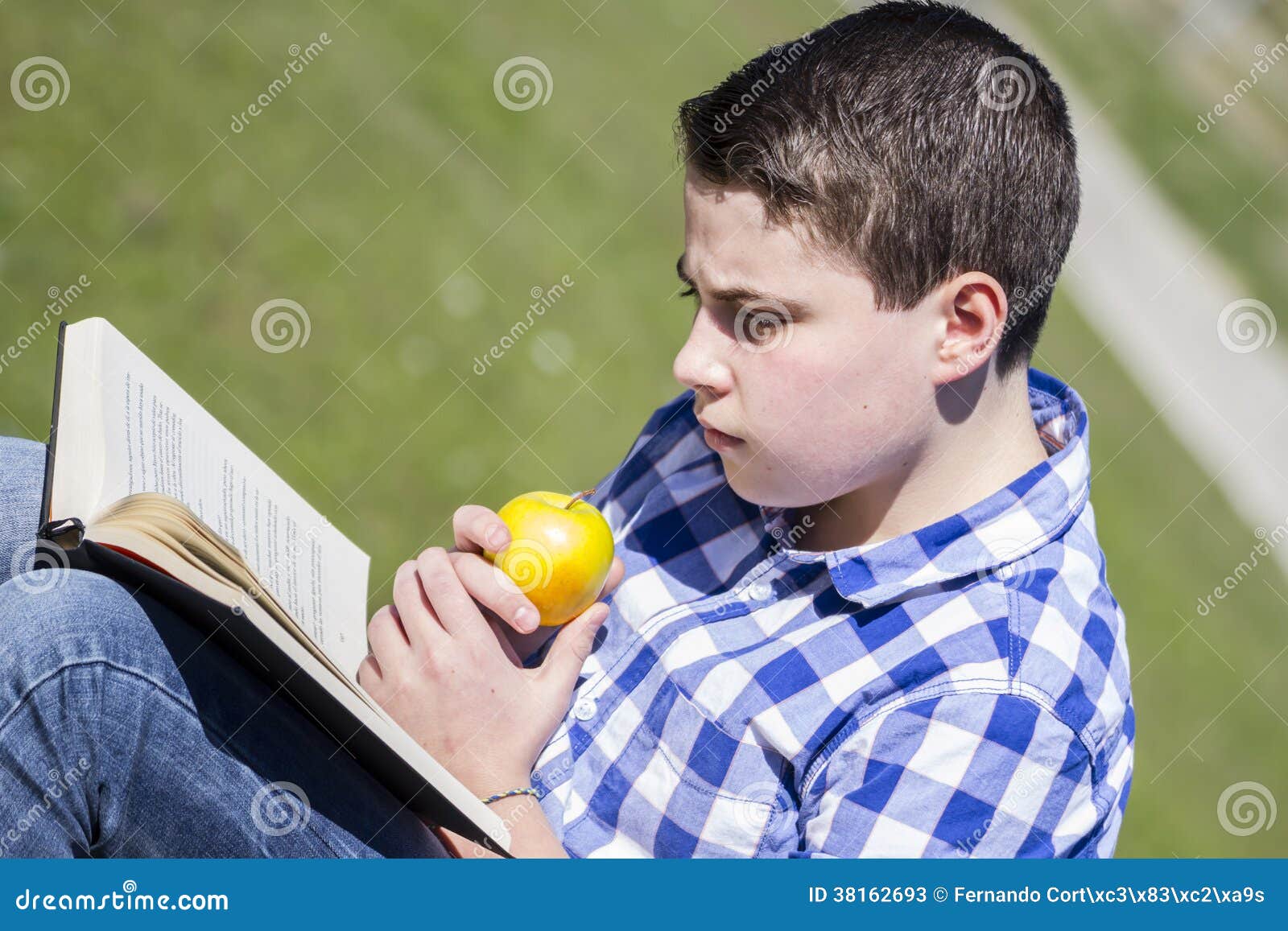 Looking.Young Man Reading a Book in Outdoor with Yellow Apple. Stock ...