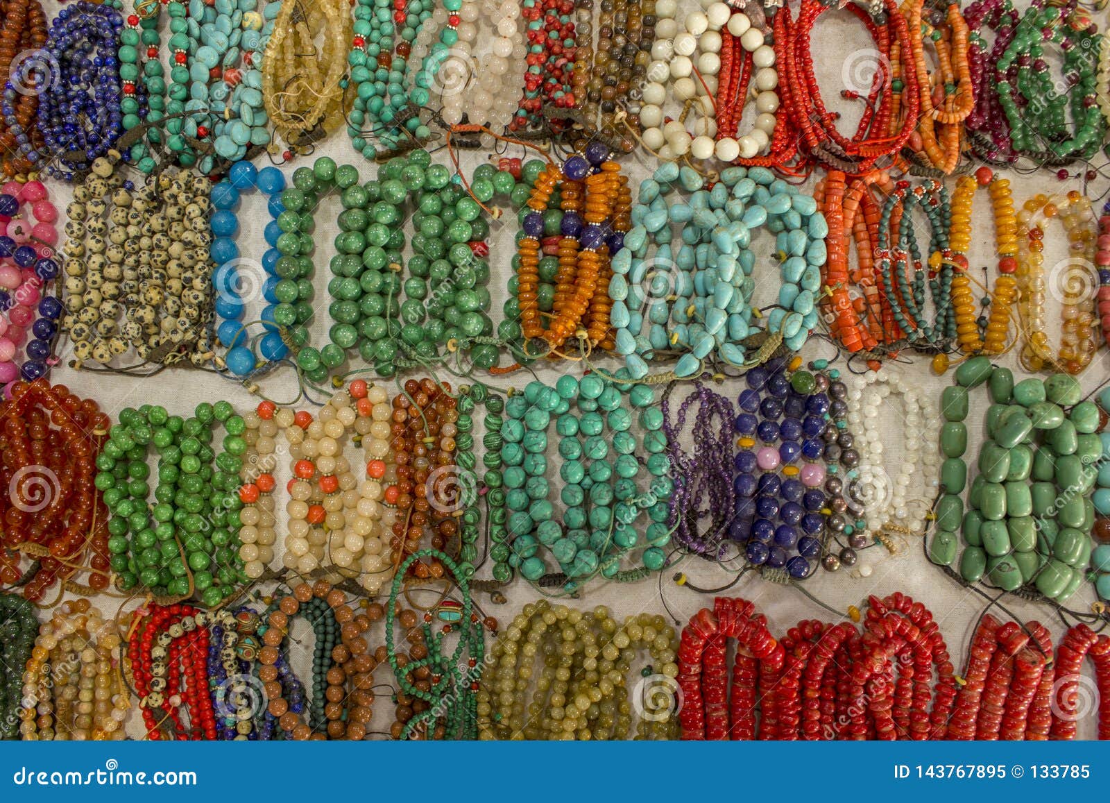 Lot of Bright Multi-colored Bracelets Made of Balls of Stones Lying on ...