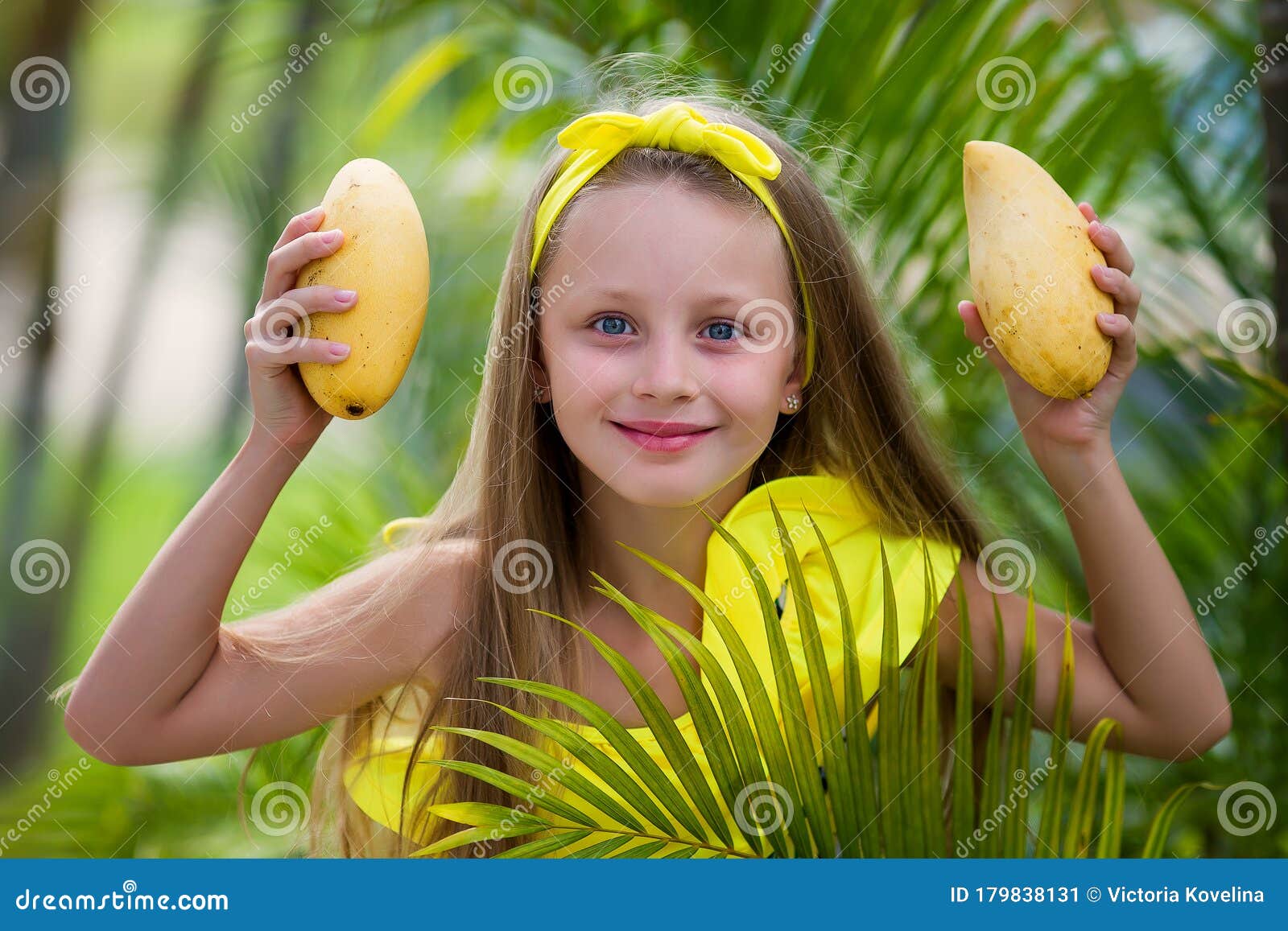 Lovely Girl In Yellow Swimsuit Holds A Yellow Mango On Vacation In The