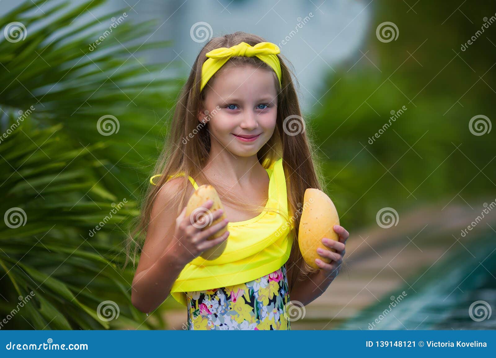 Lovely Girl In Yellow Swimsuit Holds Yellow Mango On Vacation In The