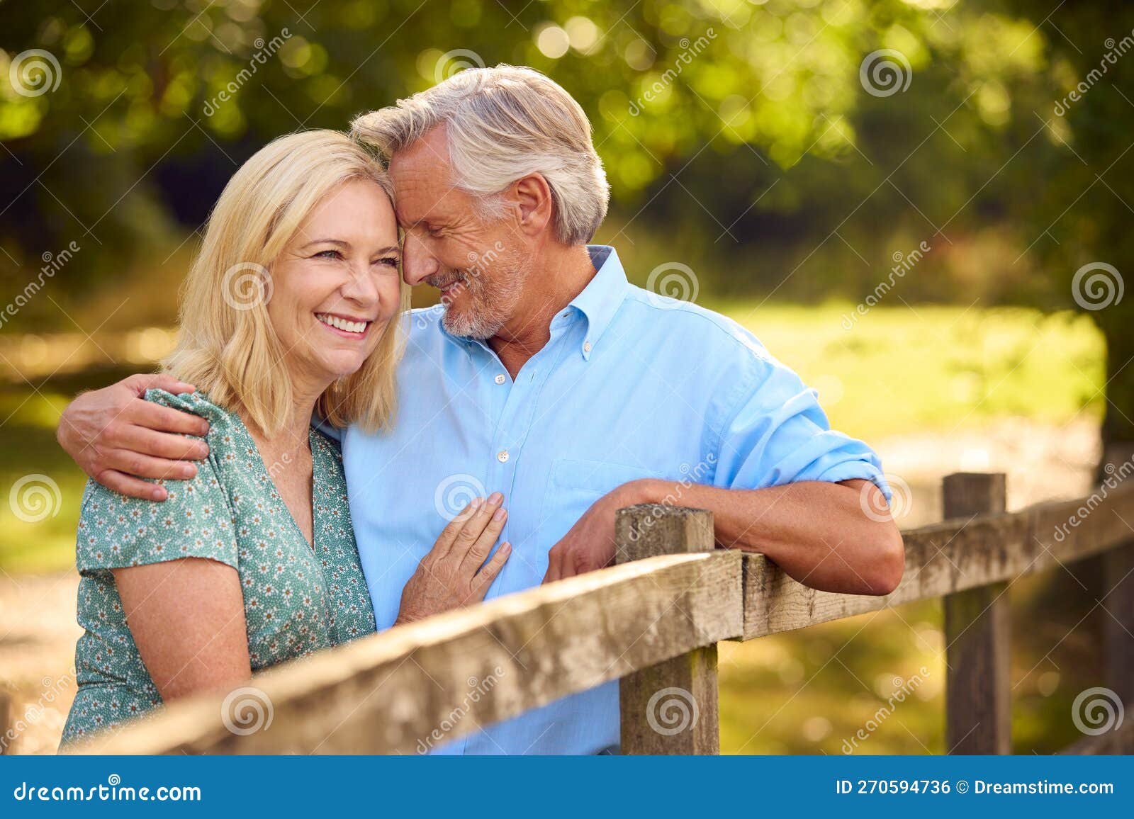 Loving Casually Dressed Mature Or Senior Couple Leaning On Fence On