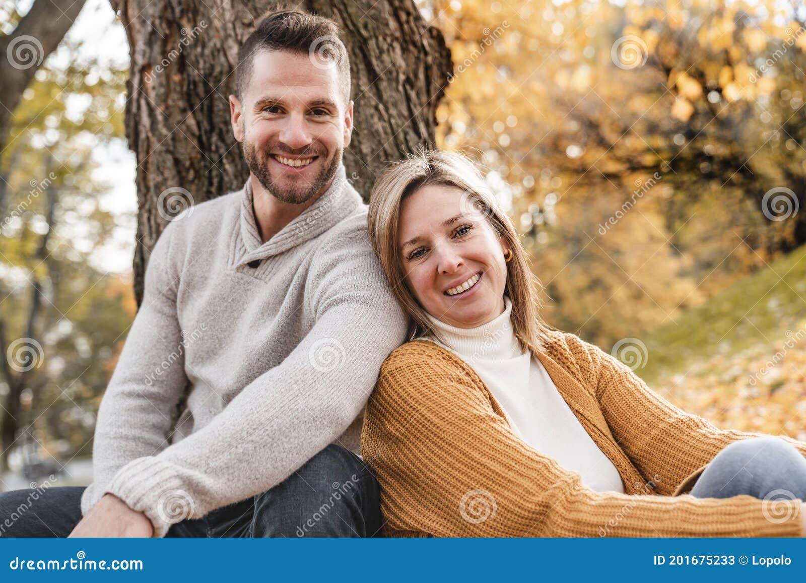 Loving Couple in the Autumn Park Sitting on the Bottom of a Tree Stock ...