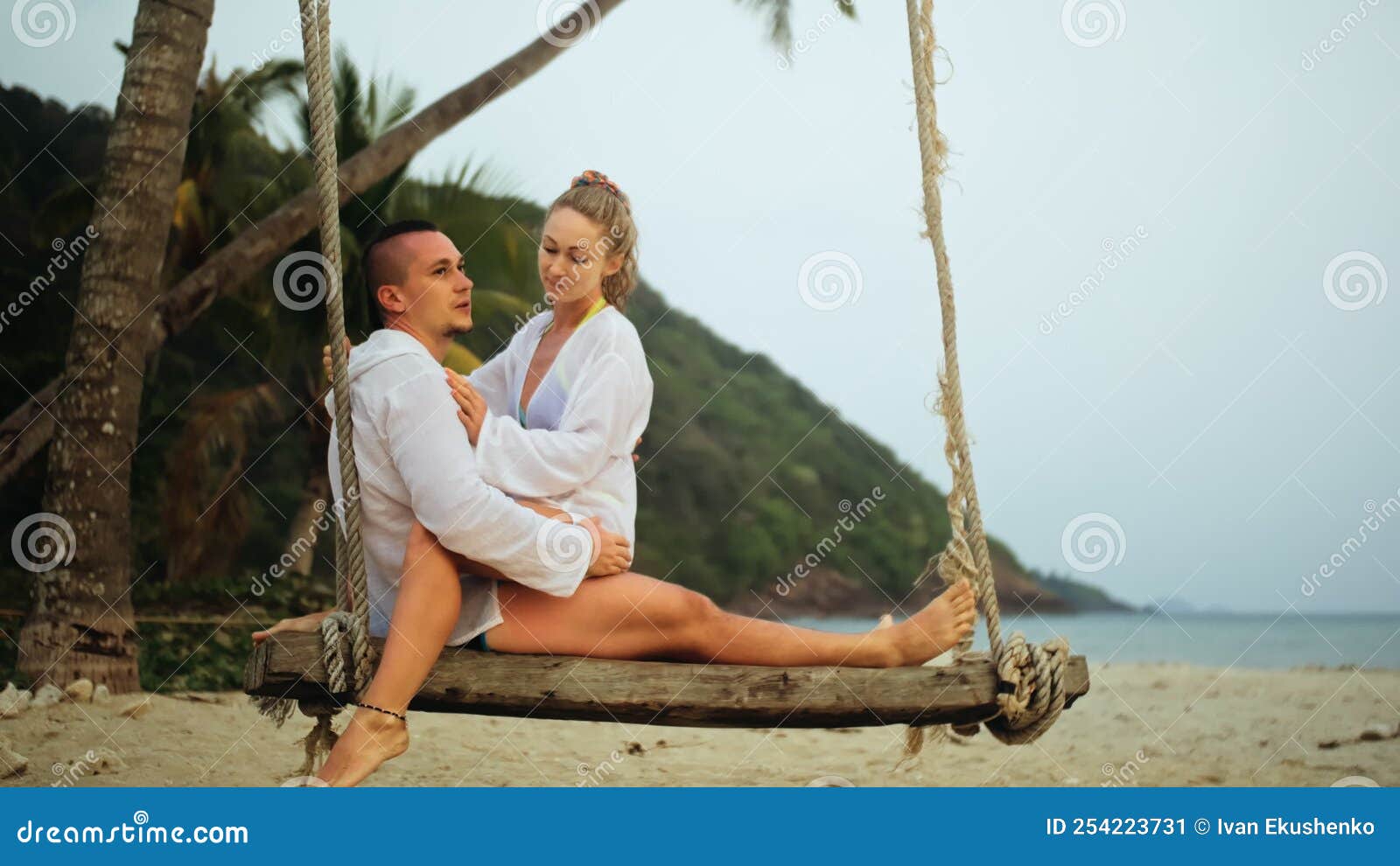 Loving Couple On The Swing On Tropical Beach Woman And Man In White