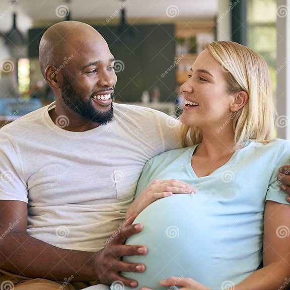 Loving Multi-Racial Couple with Pregnant Woman on Sofa at Home with ... Loving Multi-Racial Couple with Pregnant Woman on Sofa at Home with ...