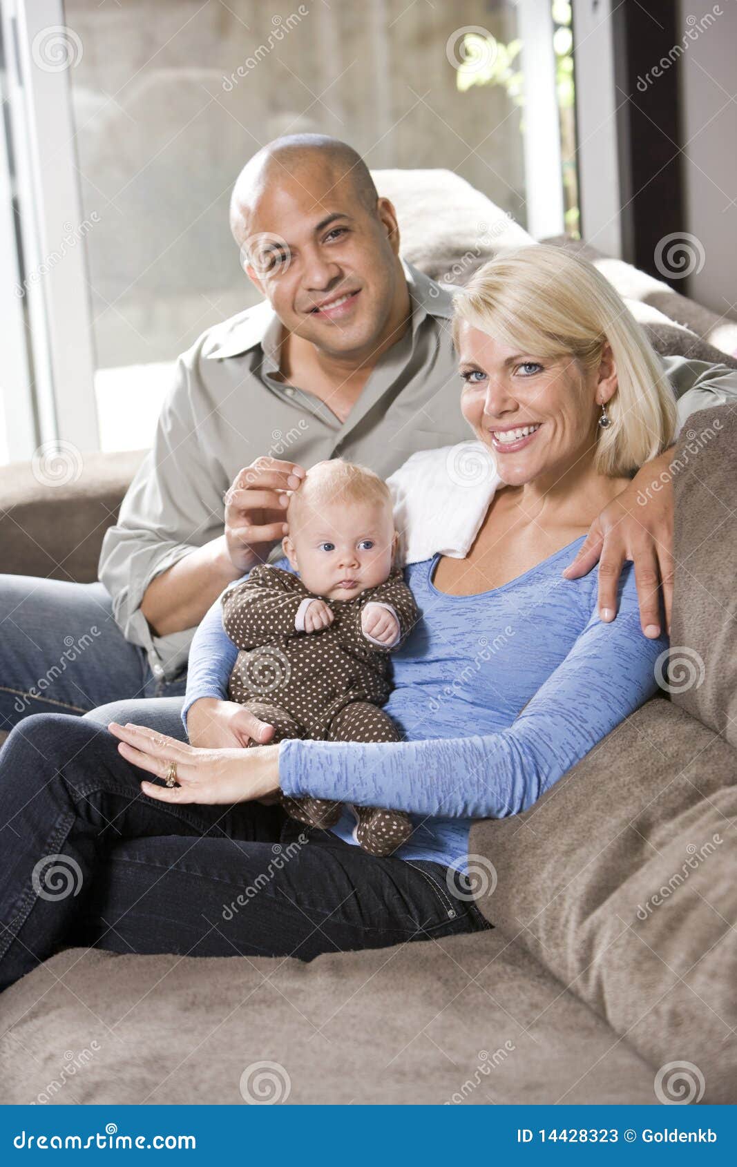 Loving Parents Sitting In Chair Cuddling Baby Son In Nursery At Home ...