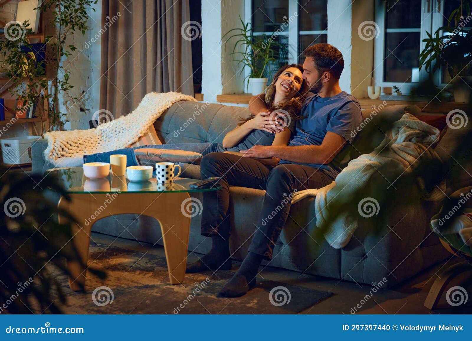 Loving Young Couple Man And Woman Sitting On Sofa In Evening At Home