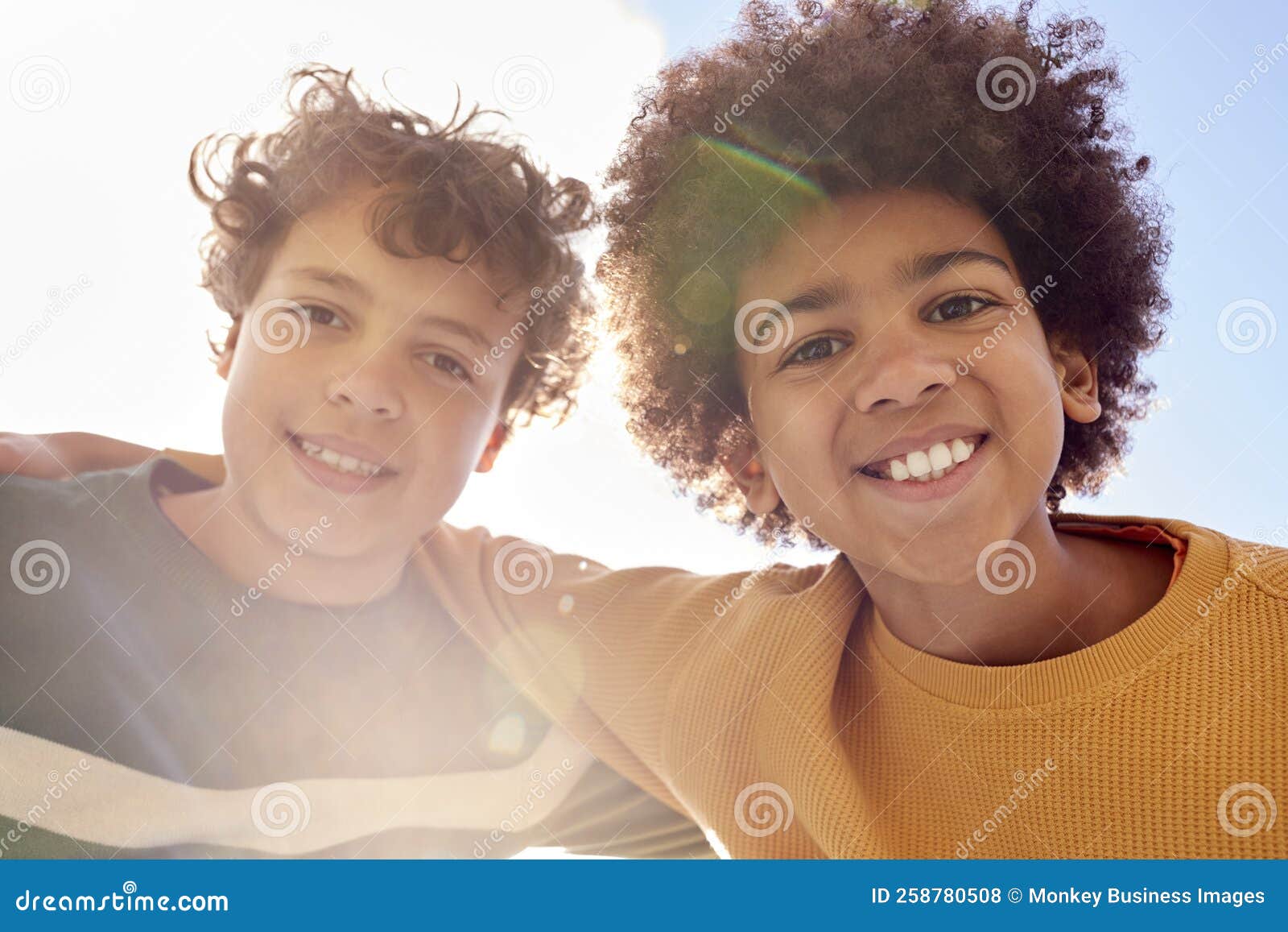 Low Angle Portrait of Two Boys Having Fun Playing Outdoors Looking Down ...