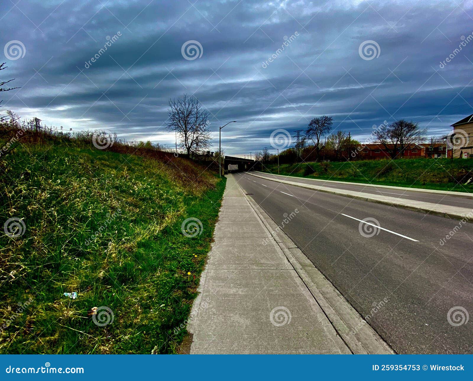Low-angle of a Road with Green Grass Around, Cloudy Gloomy Sky ...