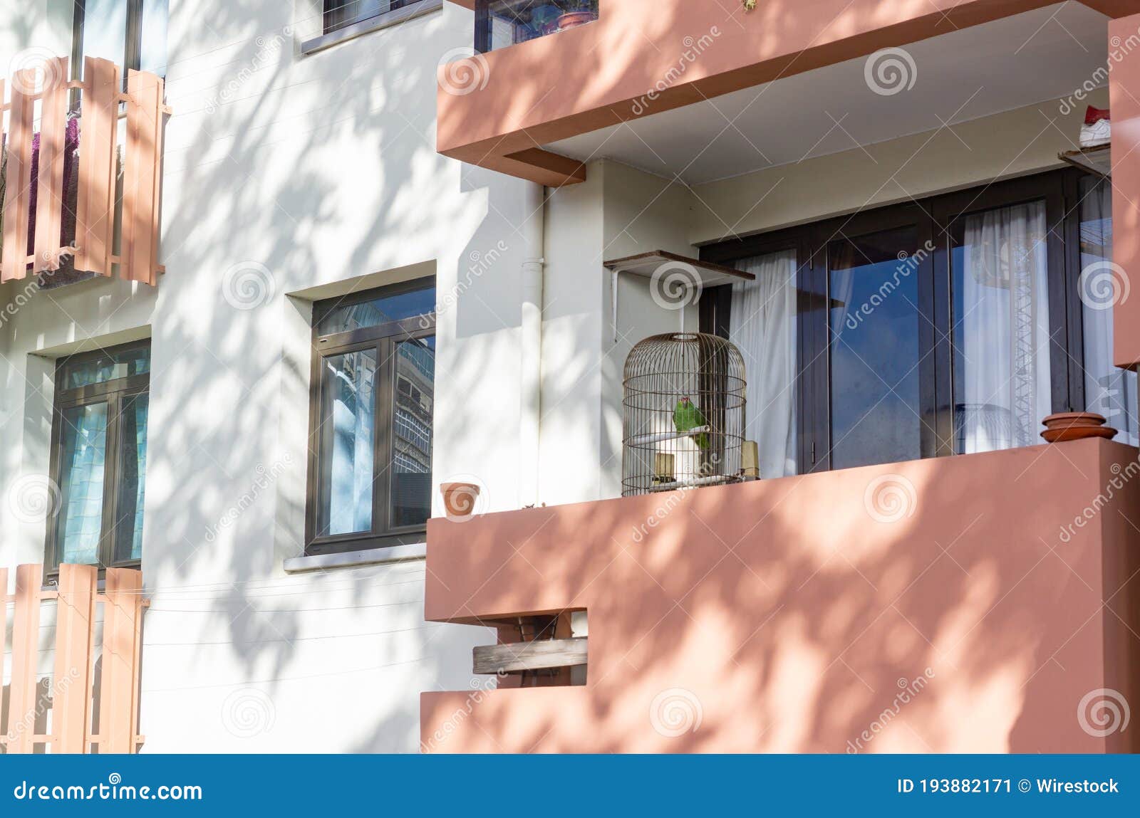 Low Angle Shot of the Facade of a Building with a Parrot Cage on the ...