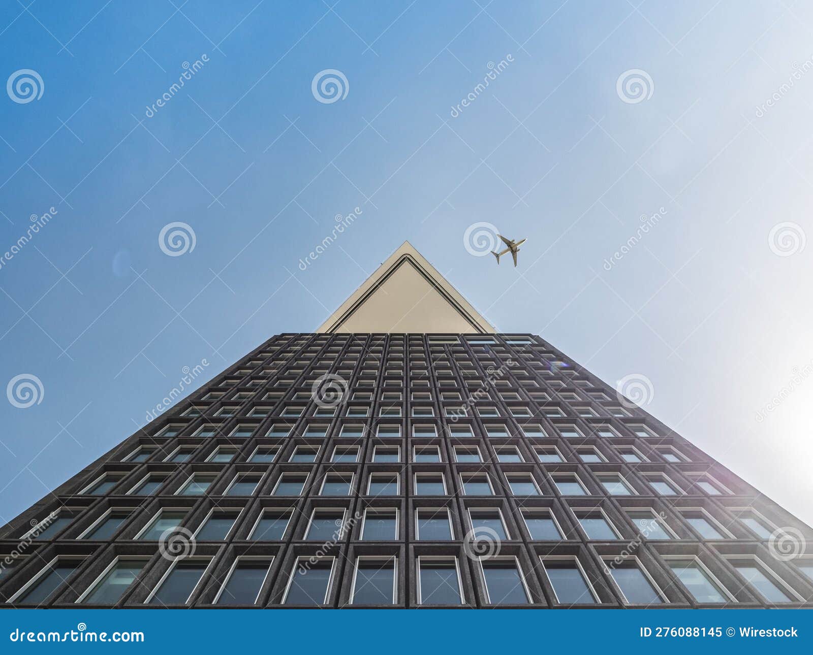 Low Angle Shot of Modern High-rise Building with an Airplane Soaring in ...