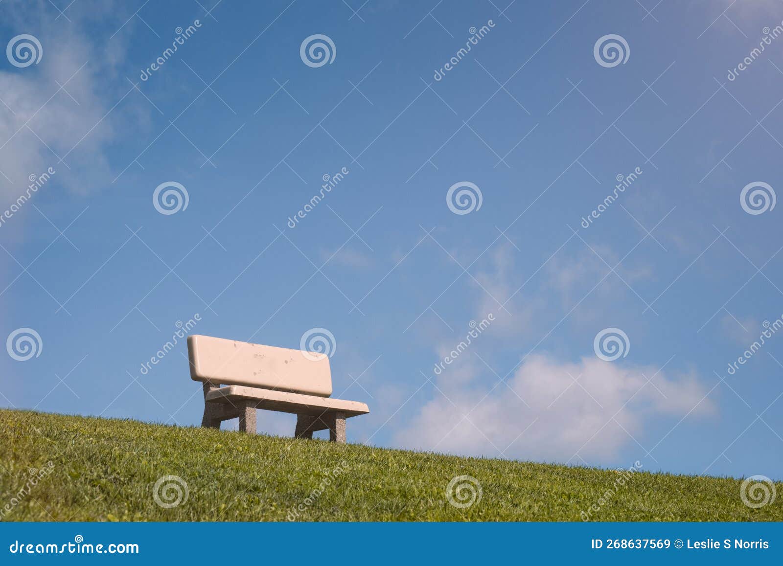 A Low-angle View of Concrete Bench on a Grassy Hill with Blue Sky ...