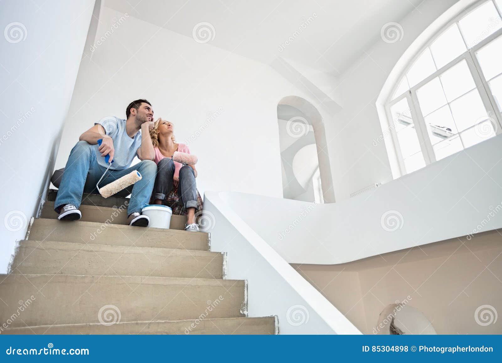 Low Angle View of Couple with Painting Tools Sitting on Steps in New ...