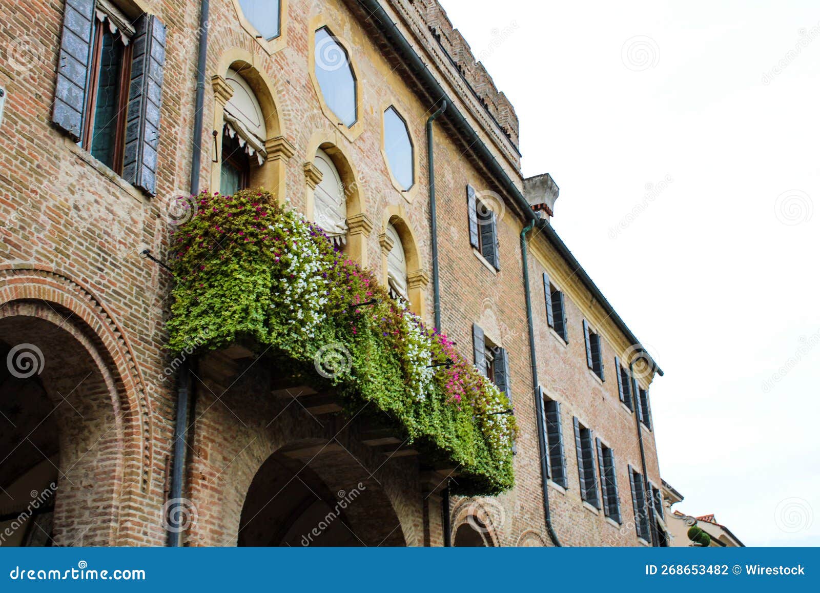 Low-angle View of a Medieval Building with a Balcony Covered in Flowers ...