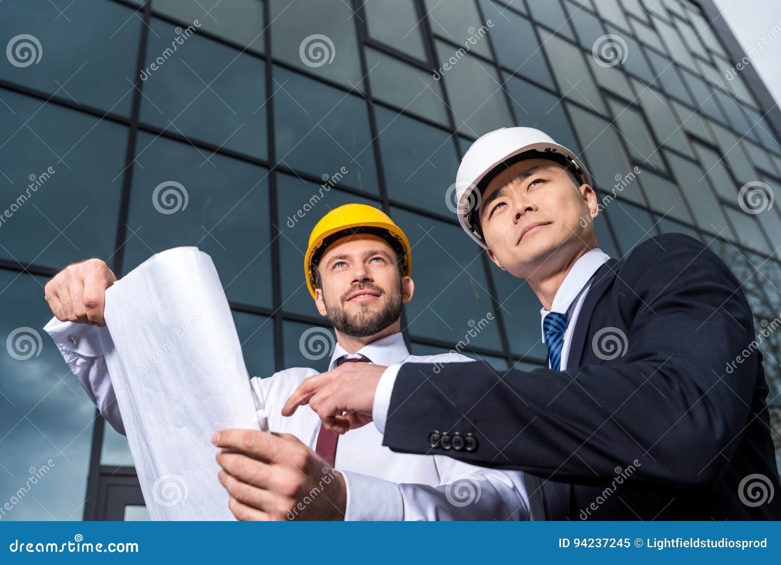 Low Angle View of Professional Architects in Hard Hats Discussing ...