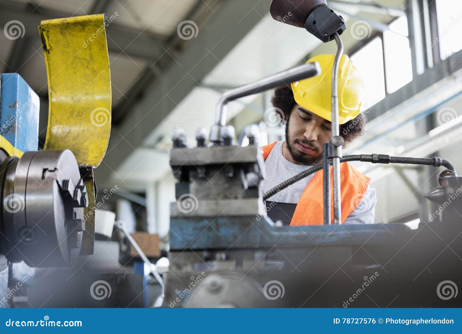 Low Angle View of Young Manual Worker Working on Machinery in Metal ...