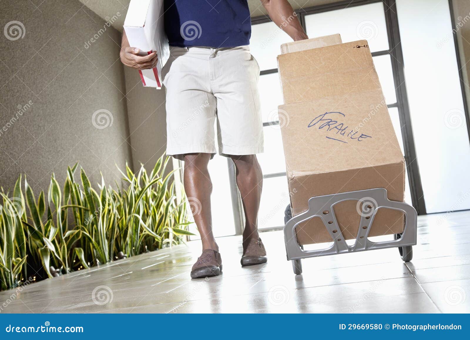 Low Section of a Man Walking with Packages on Handtruck Stock Photo ...