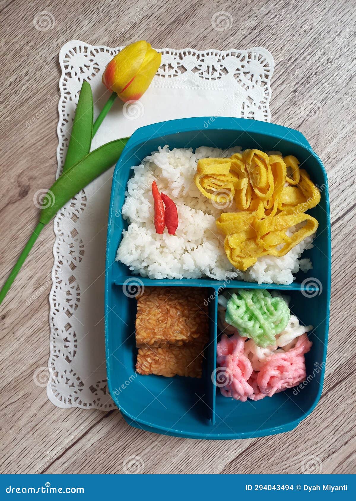A Lunch Box Containing Rice, Shredded Eggs, Tempeh and Crackers Stock ...