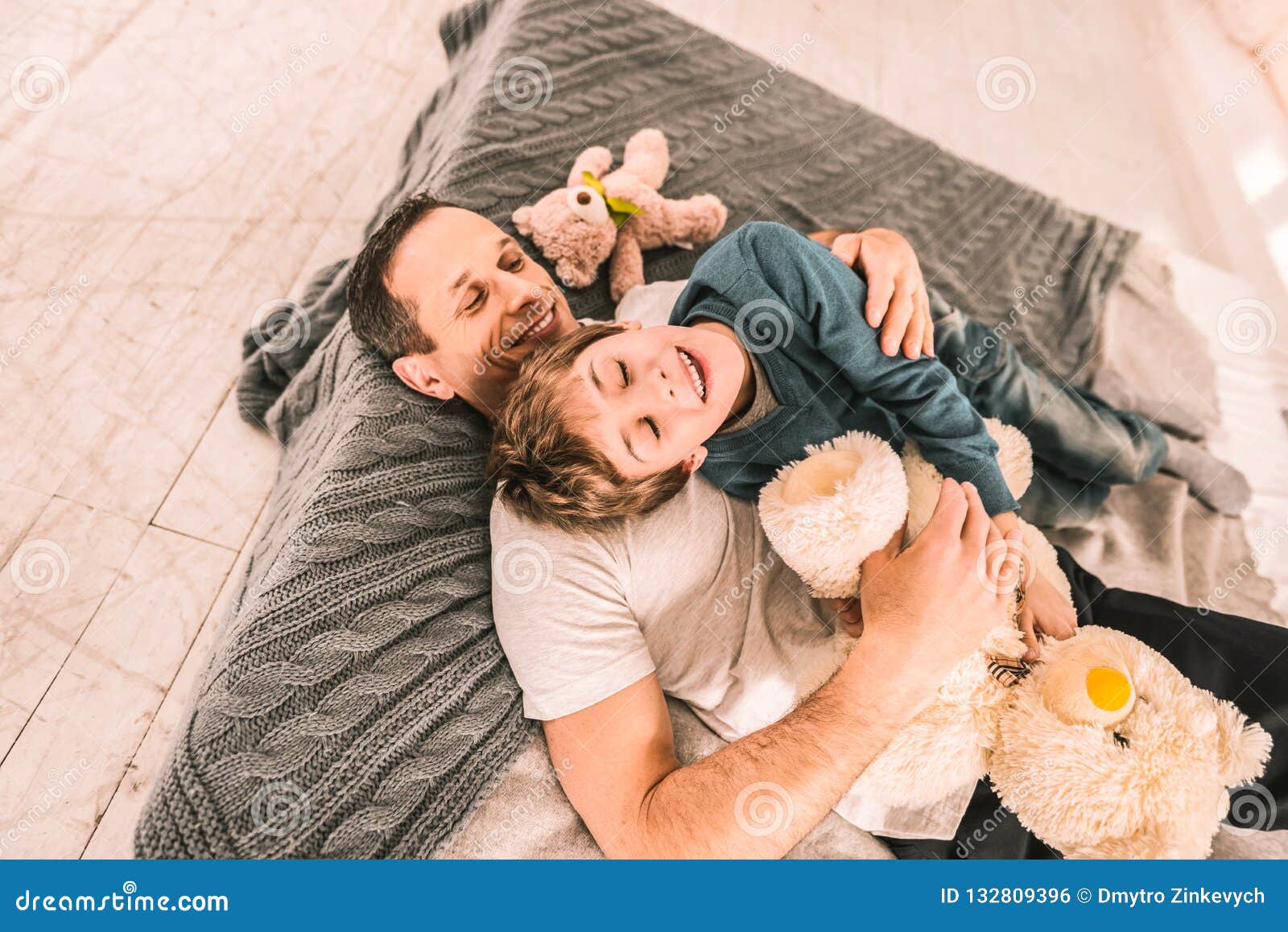 Nurturing Man Lovingly Hugging His Son while Resting on a Mattress ...