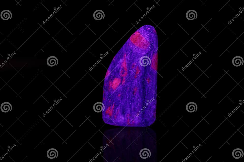 Macro Mineral Stone Ruby Under Ultraviolet Light on a Black Background ...