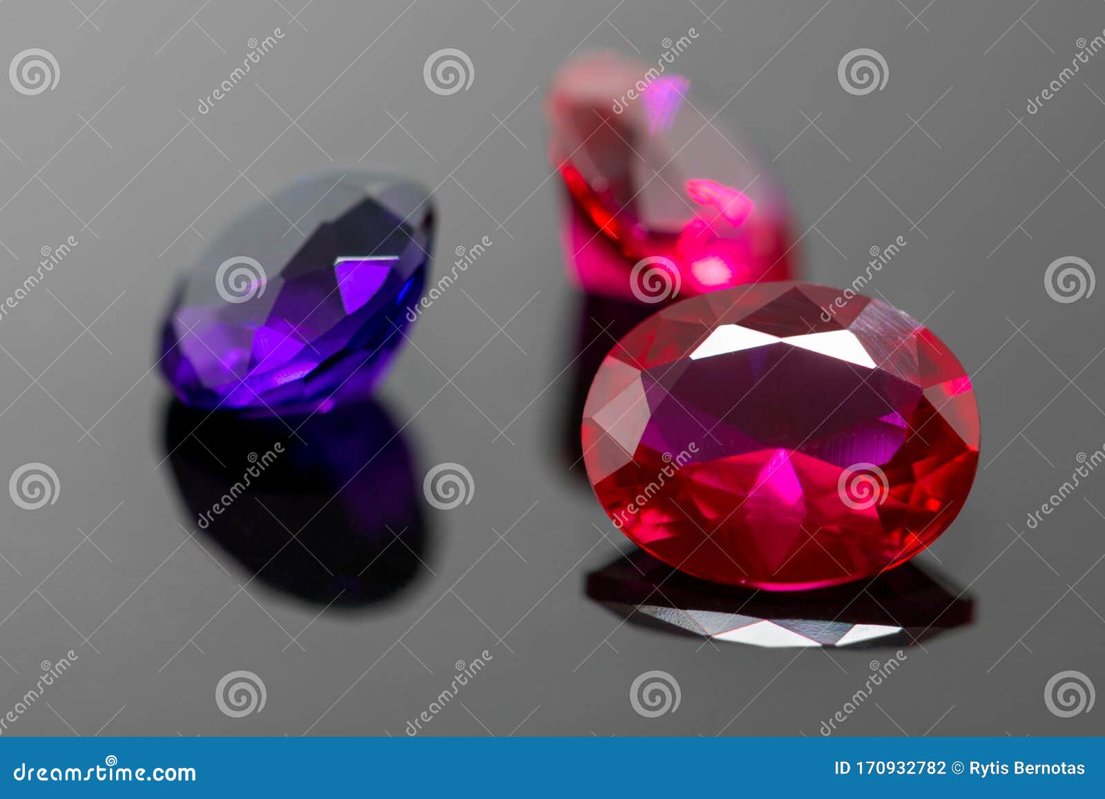 Red Rubies and Purple Amethyst Gemstones on Black Reflective Surface ...