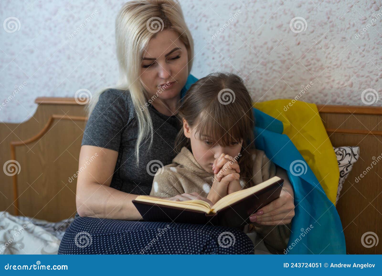 Madre E Hija Leyendo Un Libro Con La Bandera De Ucrania En La Cama ... Madre E Hija Leyendo Un Libro Con La Bandera De Ucrania En La Cama ...