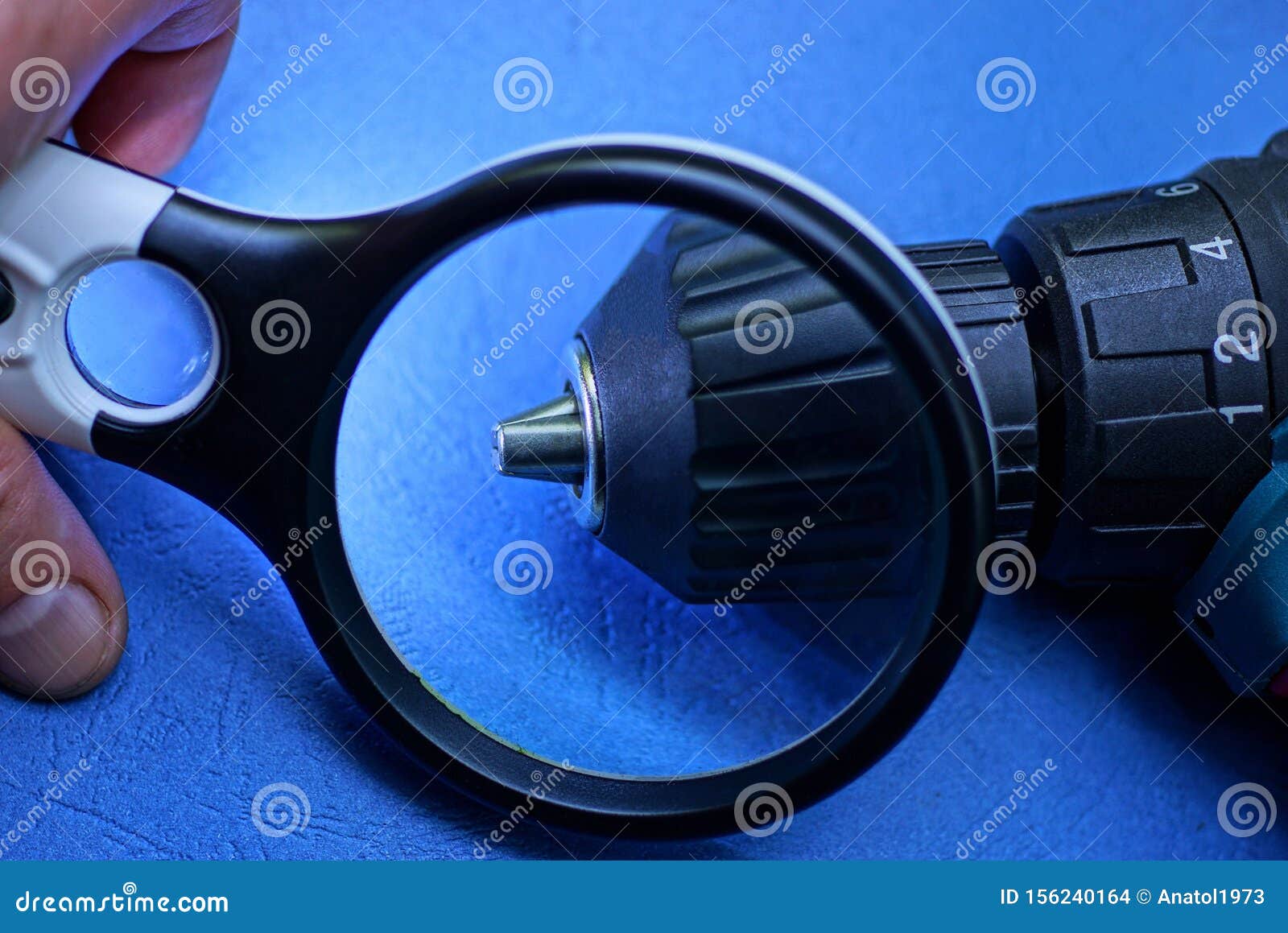Magnifier in Hand Enlarges Part of a Screwdriver on a Blue Table Stock ...