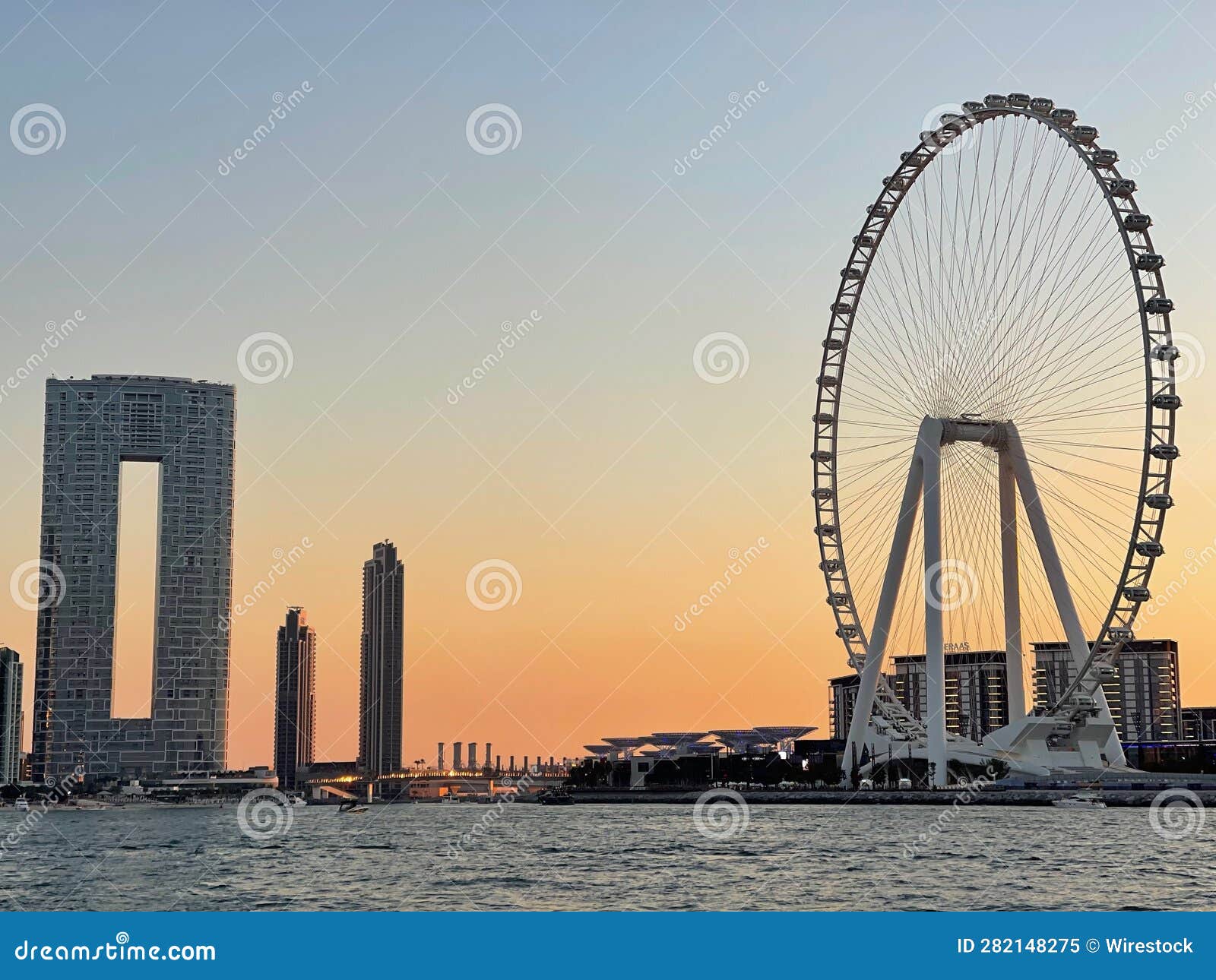 Majestic Ferris Wheel Situated in Front of the Modern Skyline at Sunset ...