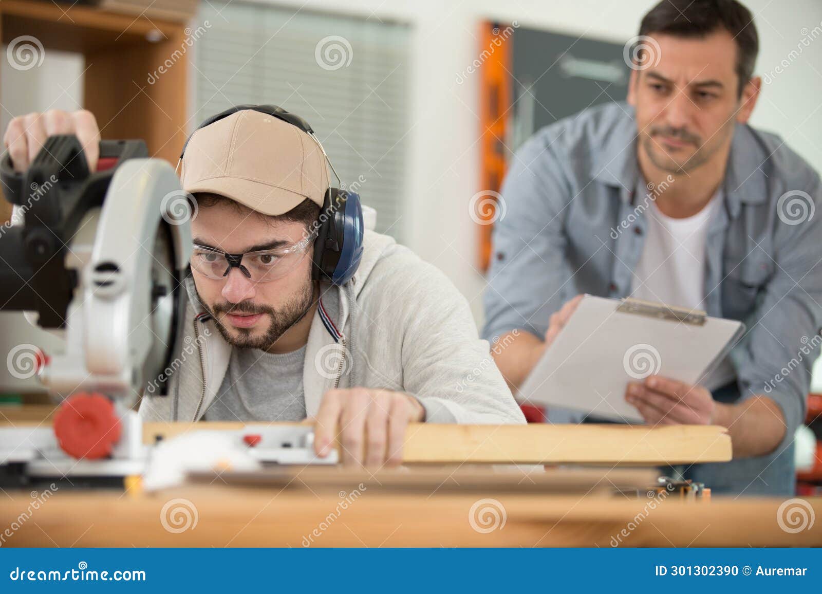 Male Apprentice Using Circular Saw Under Supervision Stock Photo ...