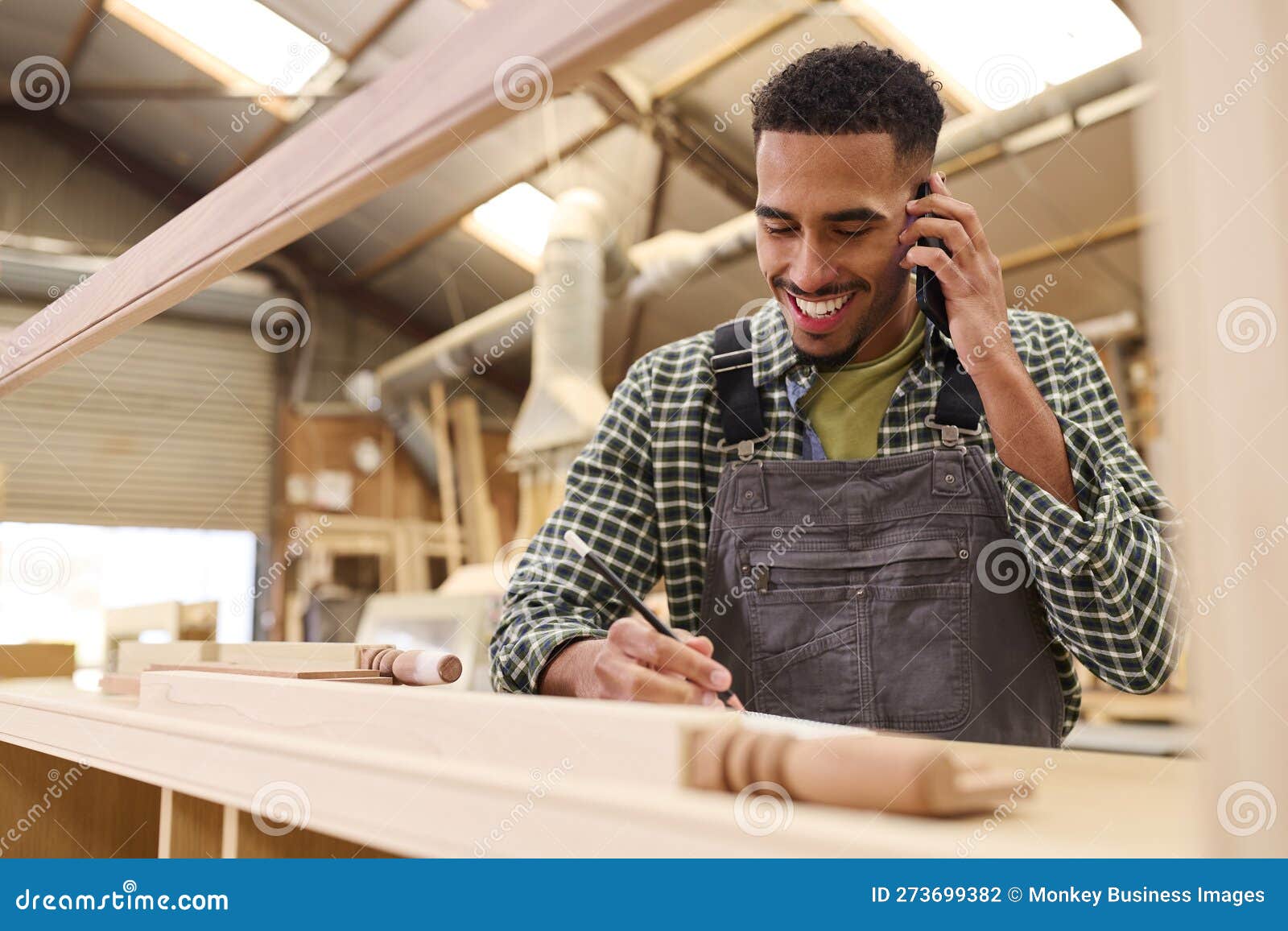 Male Apprentice Working As Carpenter in Furniture Workshop Making Phone ...