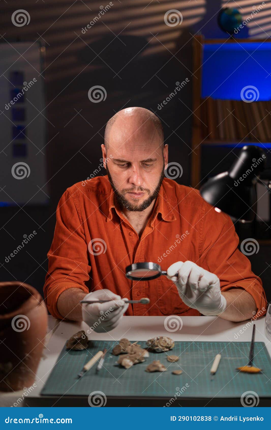Male Archaeologist Working in the Office at Night Studying Artifacts ...