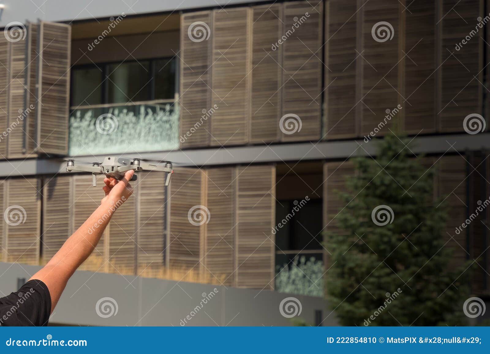 Male Arm Catching a Drone from Flight with Modern Facade in the ...