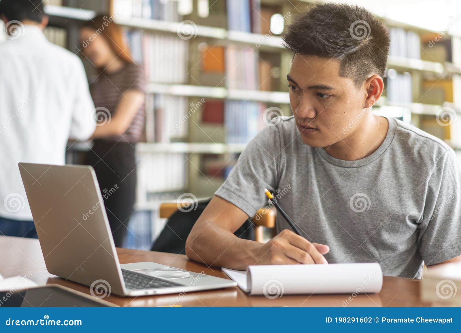 Male Asian Student Studying and Reading Book in Library Stock Photo ...