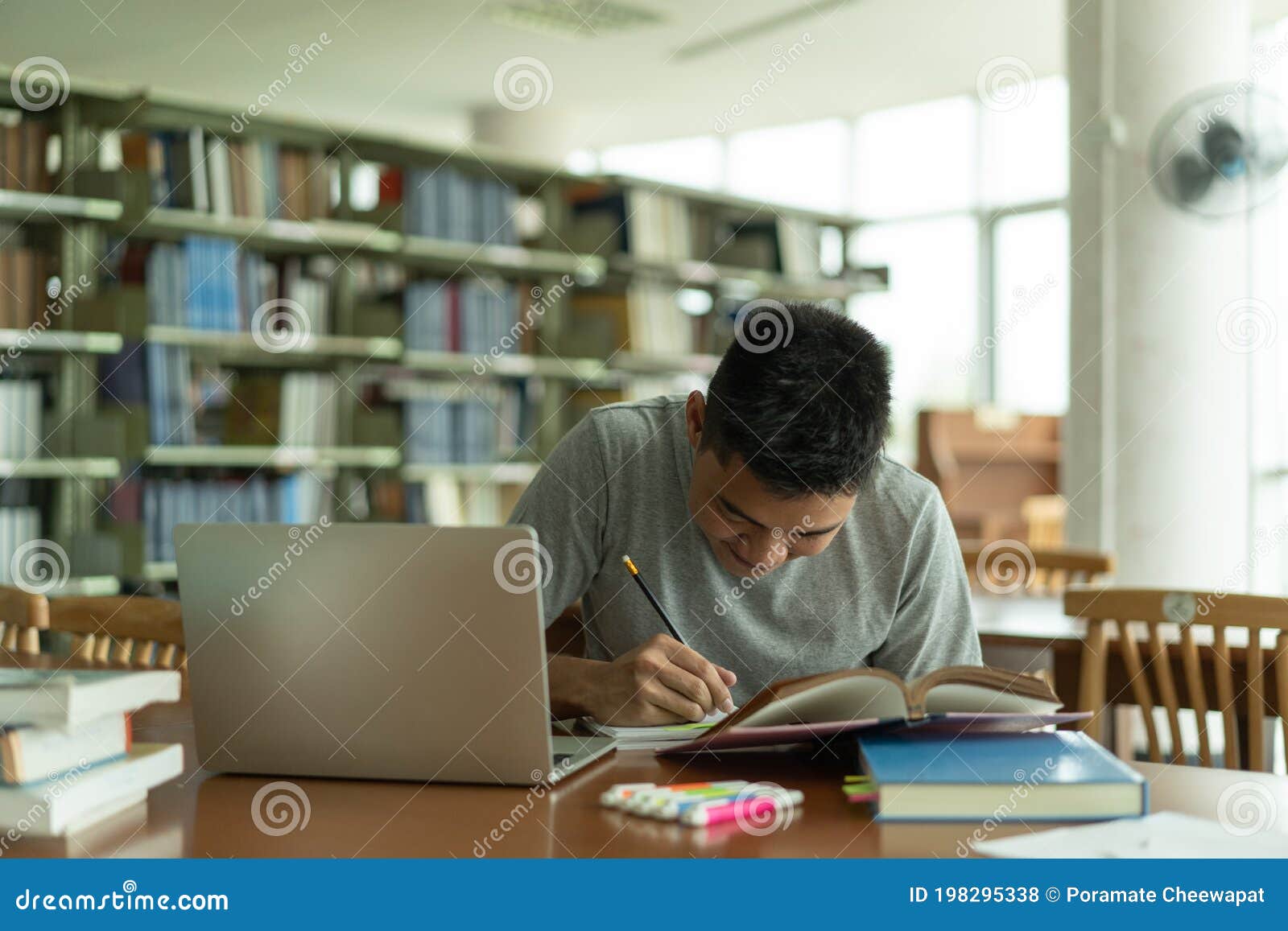 Male Asian Student Studying and Reading Book in Library Stock Photo ...