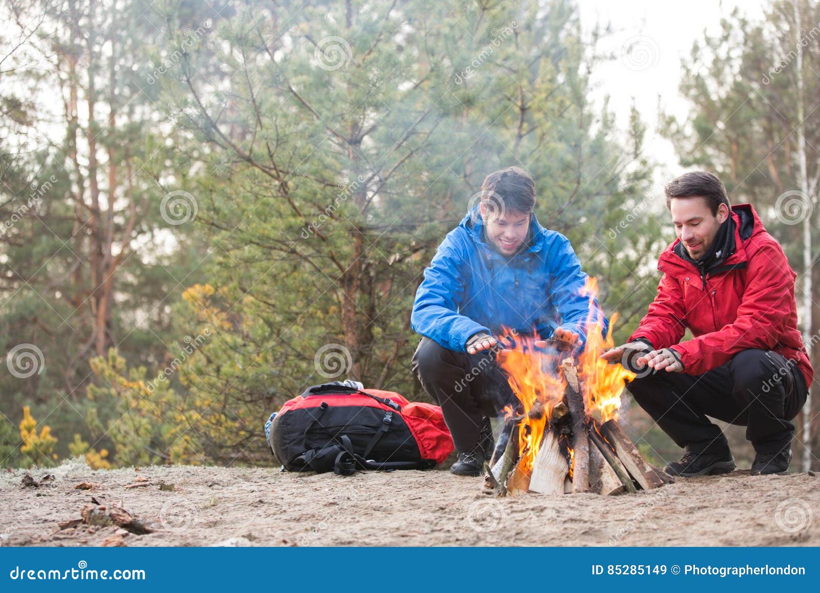 Male Backpackers Warming Hands at Campfire in Forest Stock Image ...
