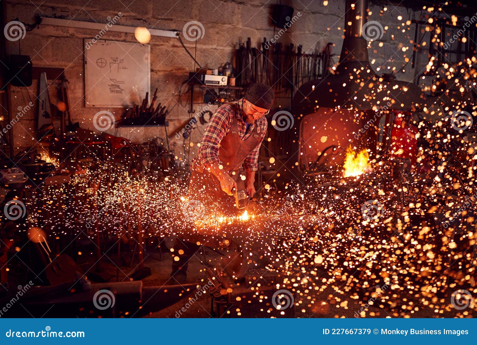 Male Blacksmith Hammering Metalwork on Anvil with Blazing Forge in ...