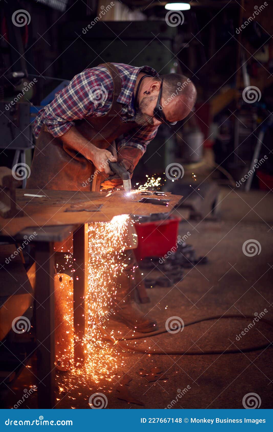Male Blacksmith Using Plasma Cutter To Cut Shape from Sheet Metal in ...