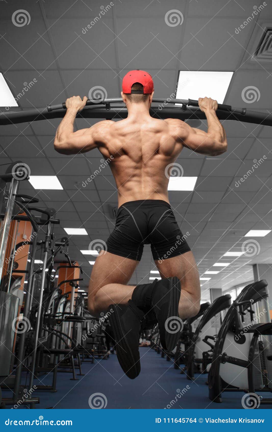 A Male Bodybuilder Performs Pull-ups on a Horizontal Bar in the Gym ...