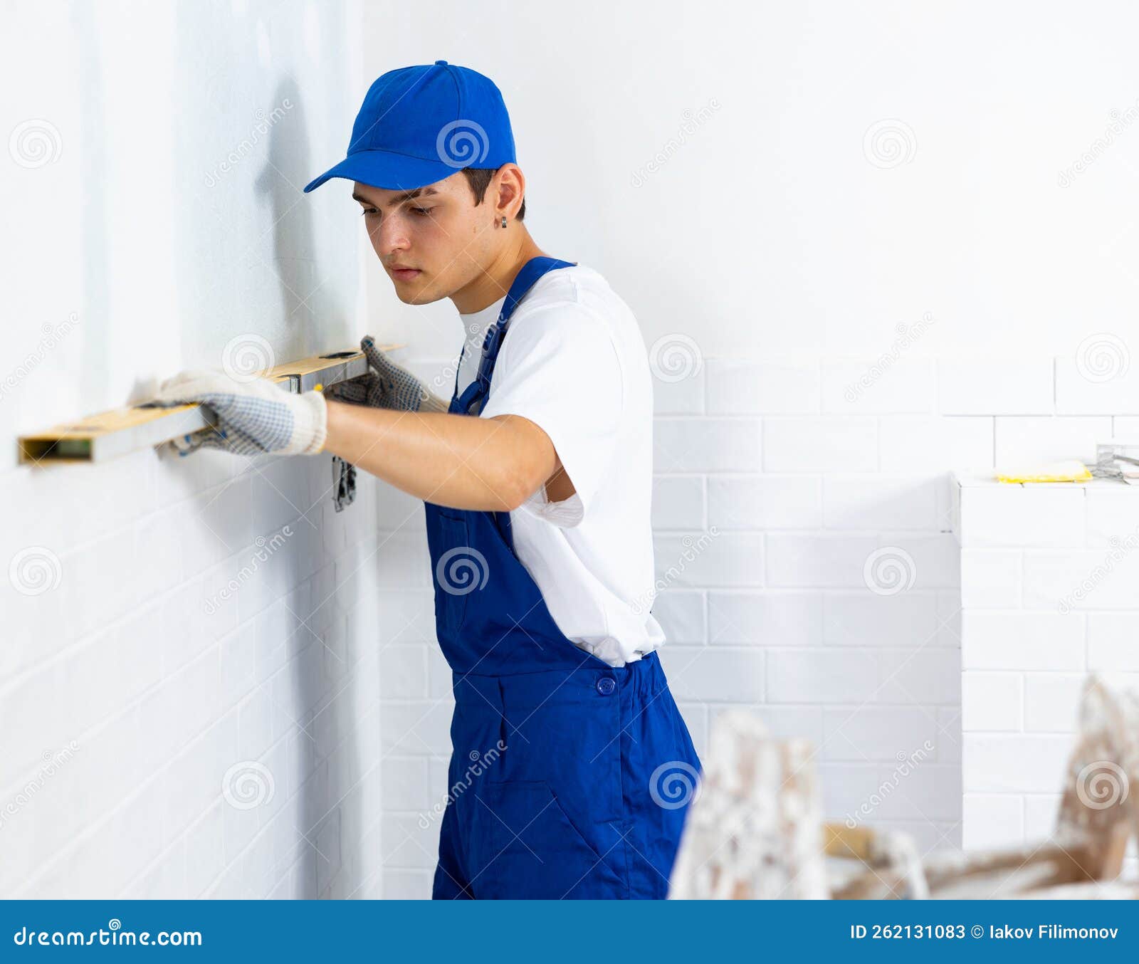 Male Builder in Blue Overalls Measures Deviations from a Given Vertical ...