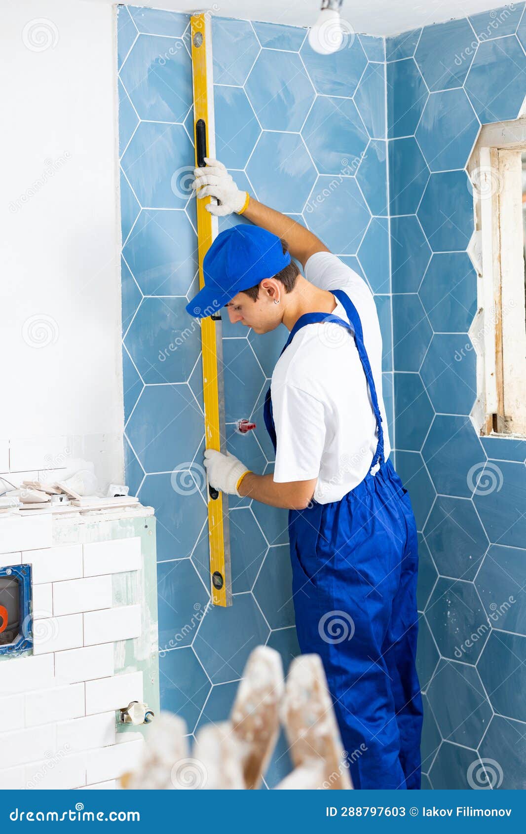 Male Builder in Blue Overalls Measures Deviations from a Given Vertical ...