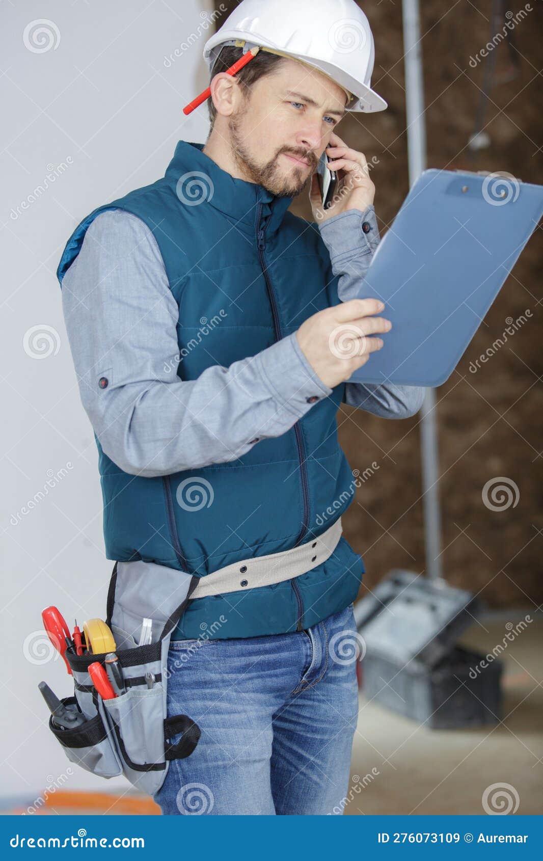 Male Builder Looking at Clipboard and Talking on Telephone Stock Image ...