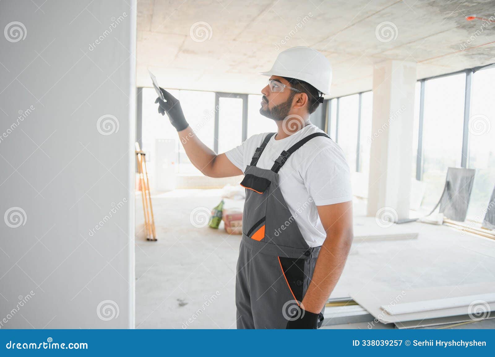 Indian Male Builder in Work Overalls Plastering a Wall Using a ...